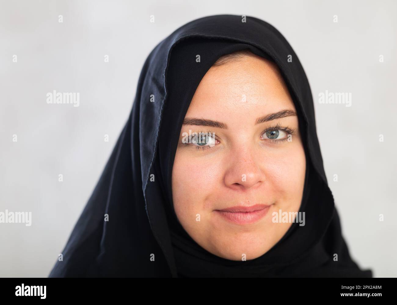 young calm Muslim woman in traditional hijab clothes poses on gray ...