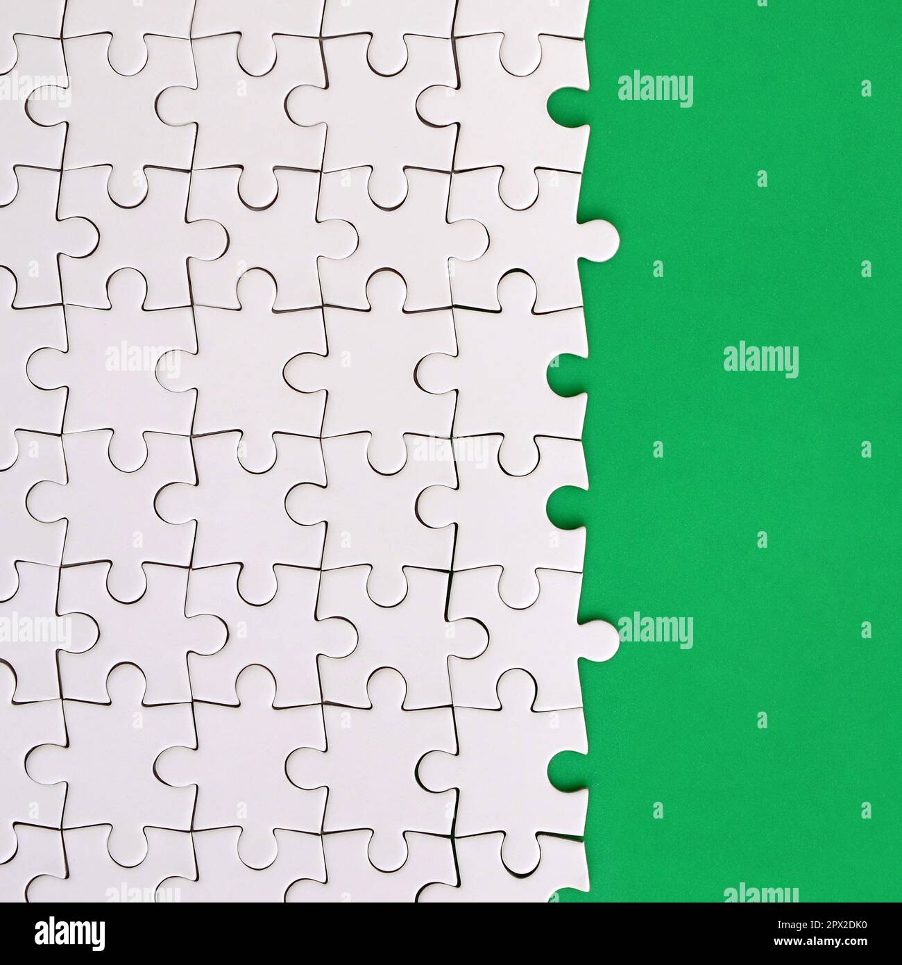 Fragment of a folded white jigsaw puzzle on the background of a green ...