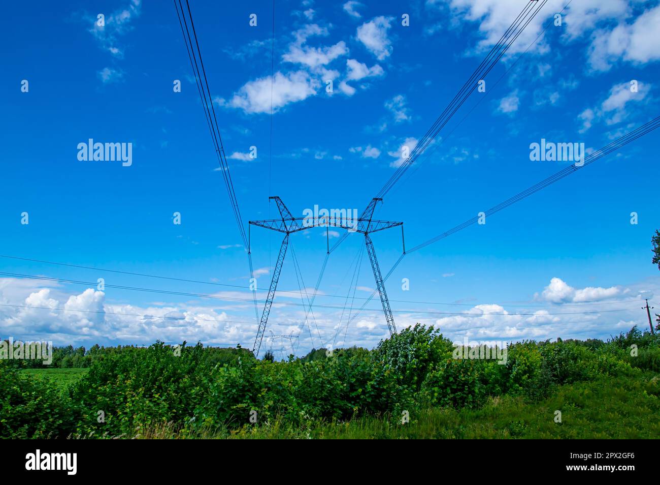 Tower with high-voltage energy transmission wires against the blue sky ...