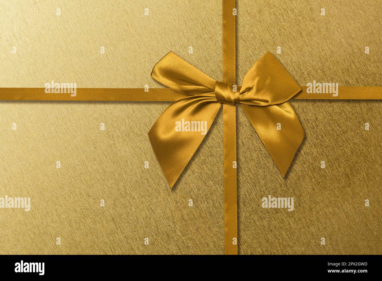 Gold ribbon with bow on a golden background. Luxury shiny gold gift box ...