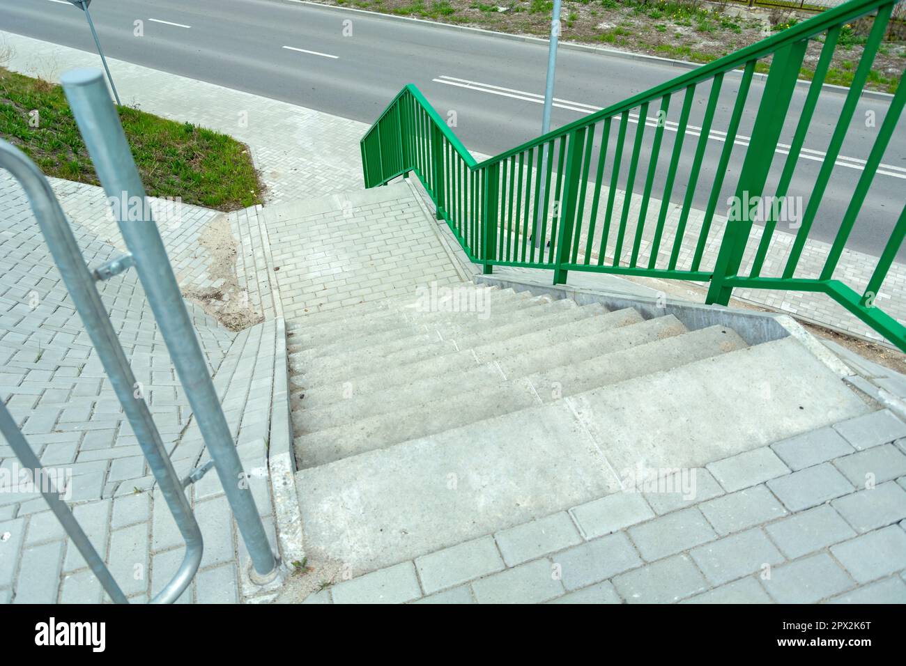 Concrete steps with green railing down the street Stock Photo - Alamy