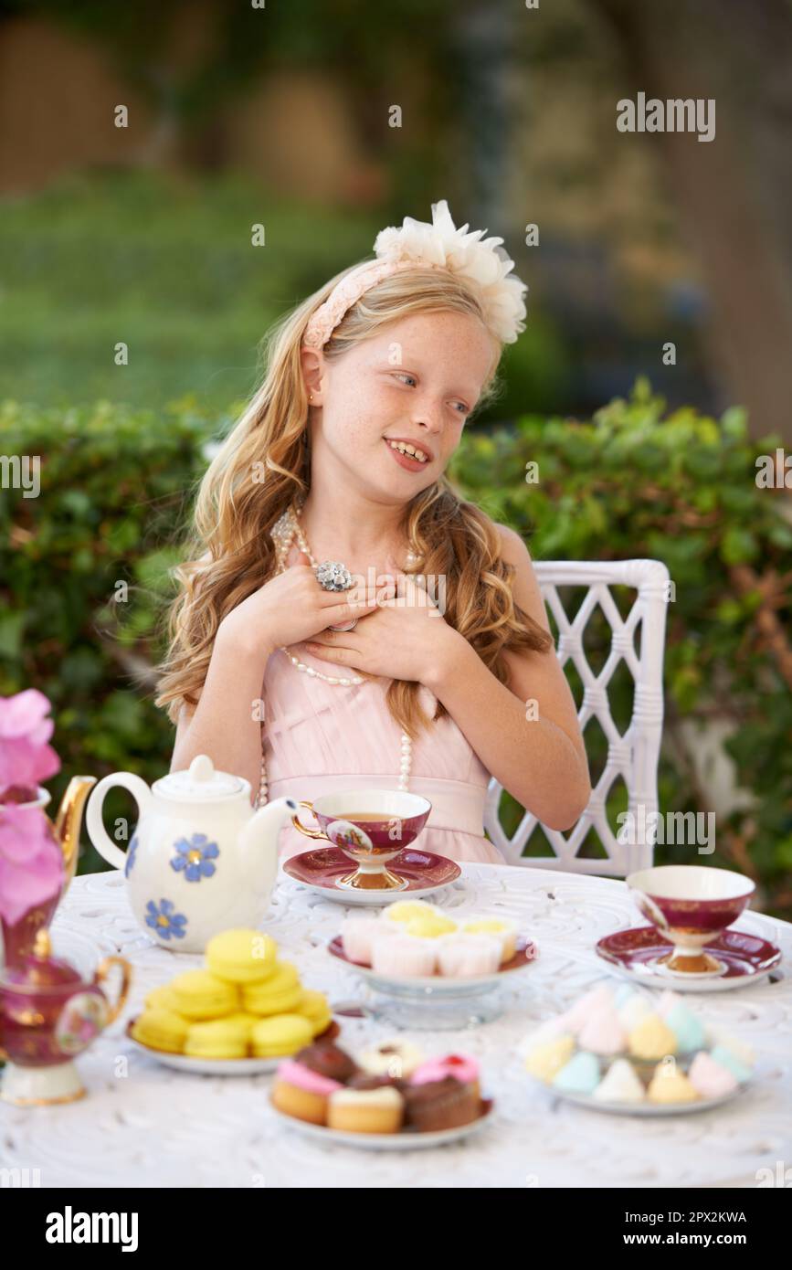 Hosting a pretend tea party. A cute little girl having a tea party ...