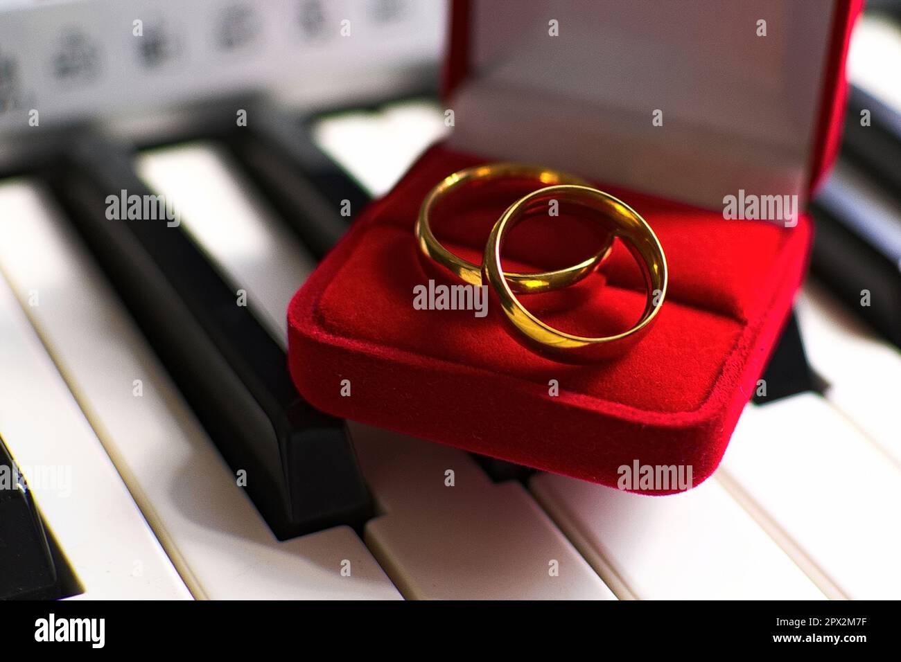 wedding rings on top of piano/keyboard keys. The image conveys the idea ...