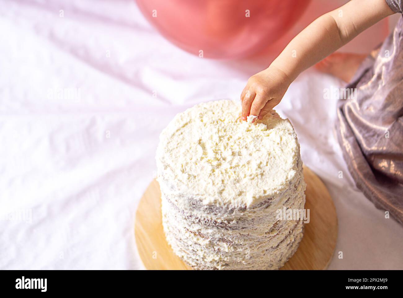 Hand of the little girl is smashing a beautiful delicious cake for ...