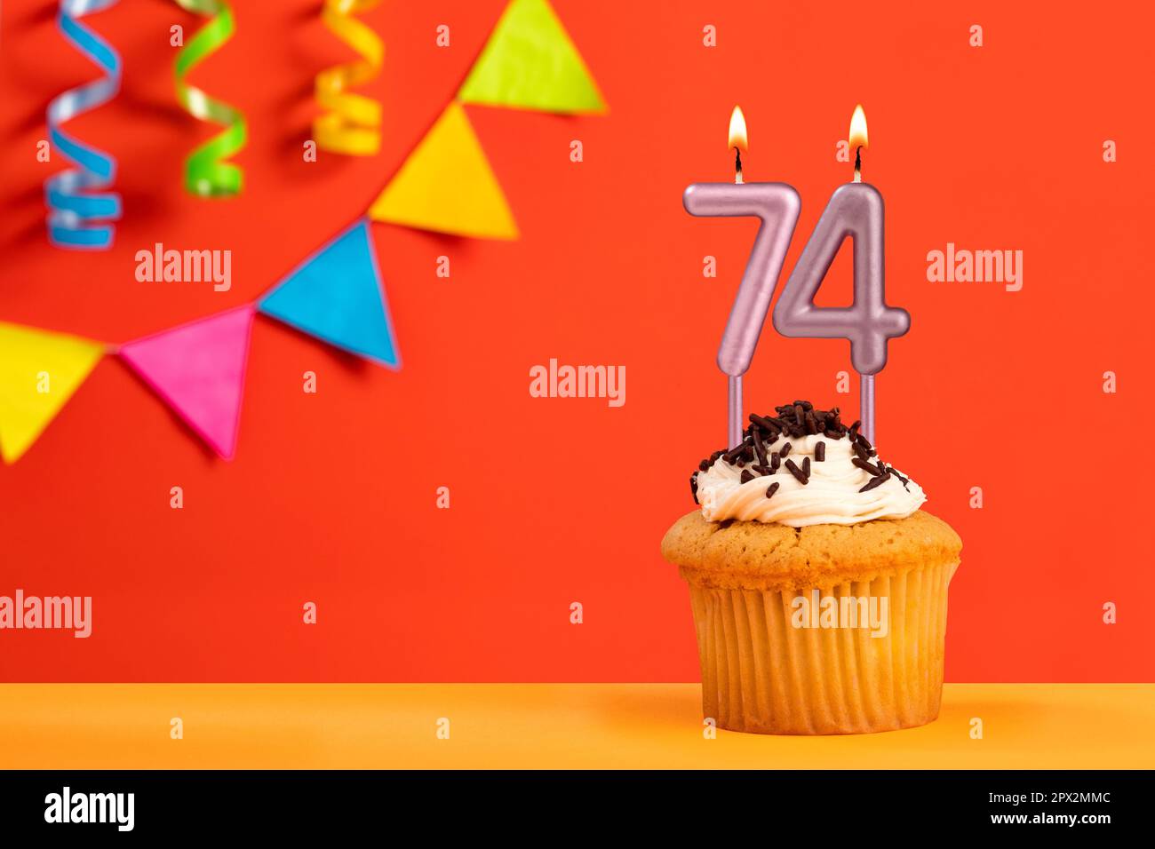 Birthday cake with number 74 candle - Sparkling orange background with ...