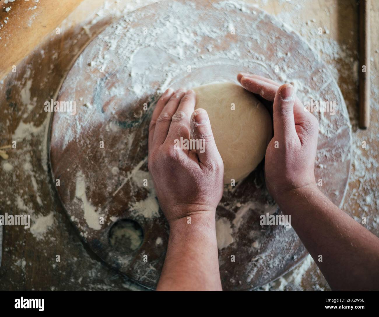 Top view of man kneading pizza dough in the kitchen. Closeup on baker's ...
