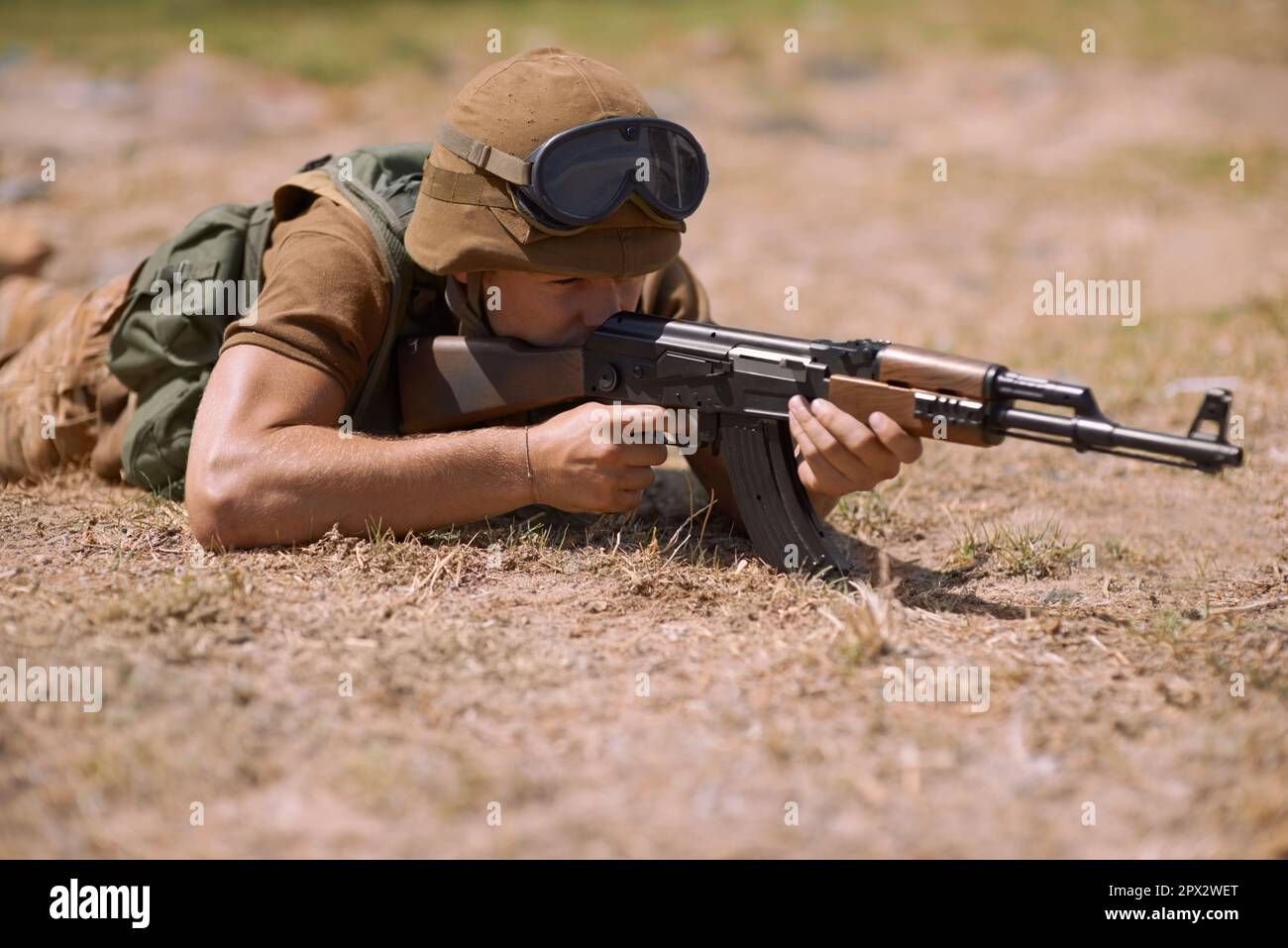 Stalking the enemy. A young soldier aiming with his rifle while lying ...