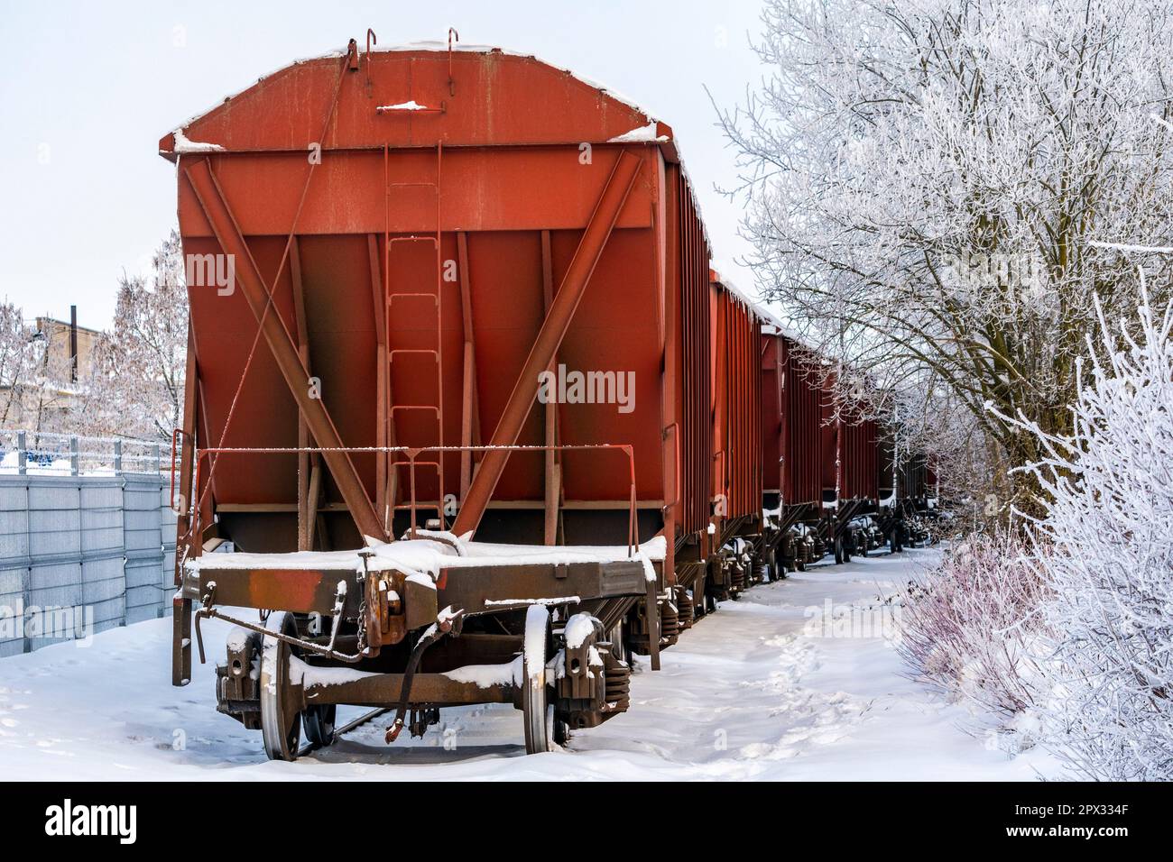 Carriages of a cargo train rides through a snow covered railway line ...