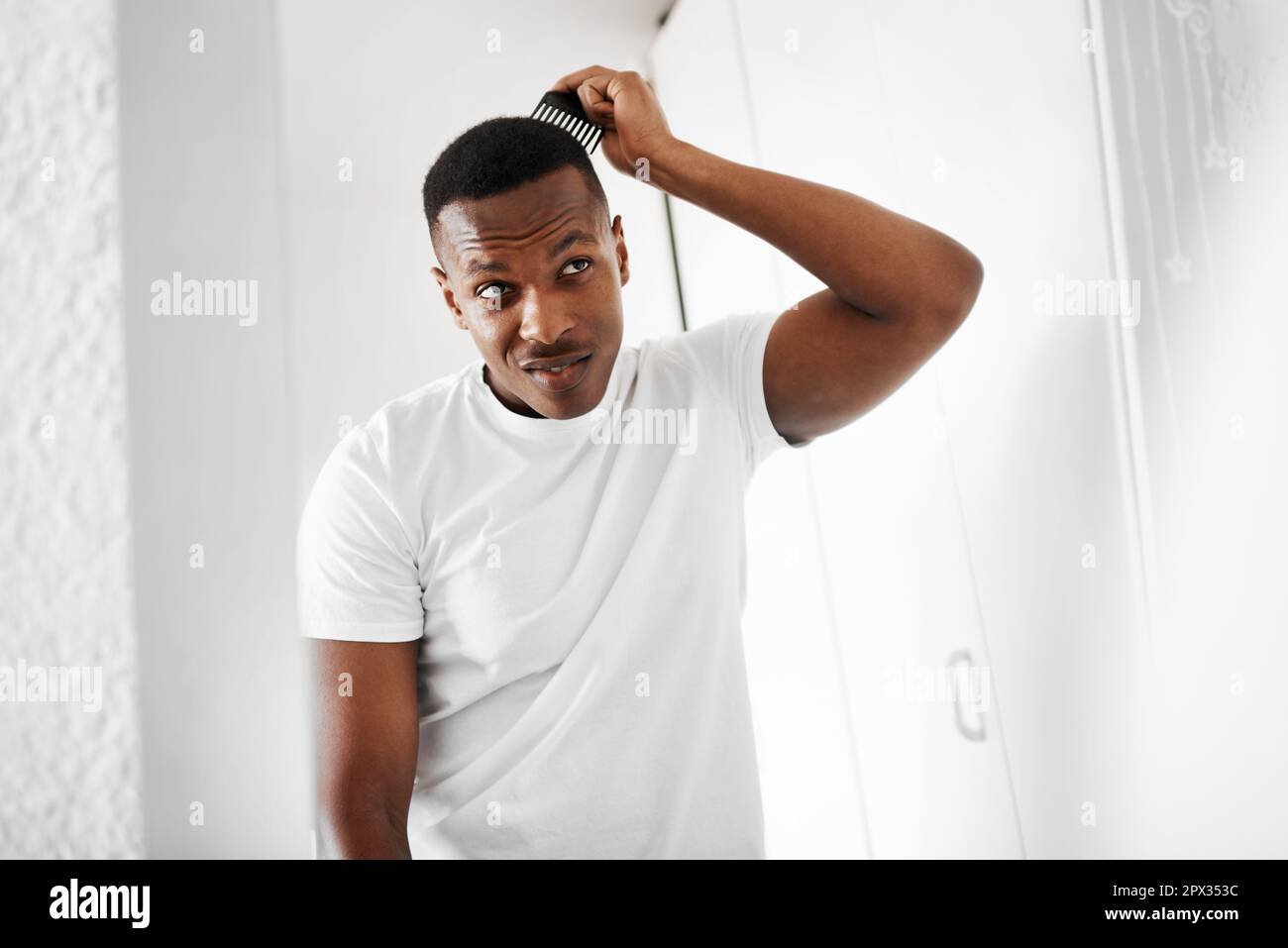 Getting ready for the day. a handsome young man combing his hair in the ...