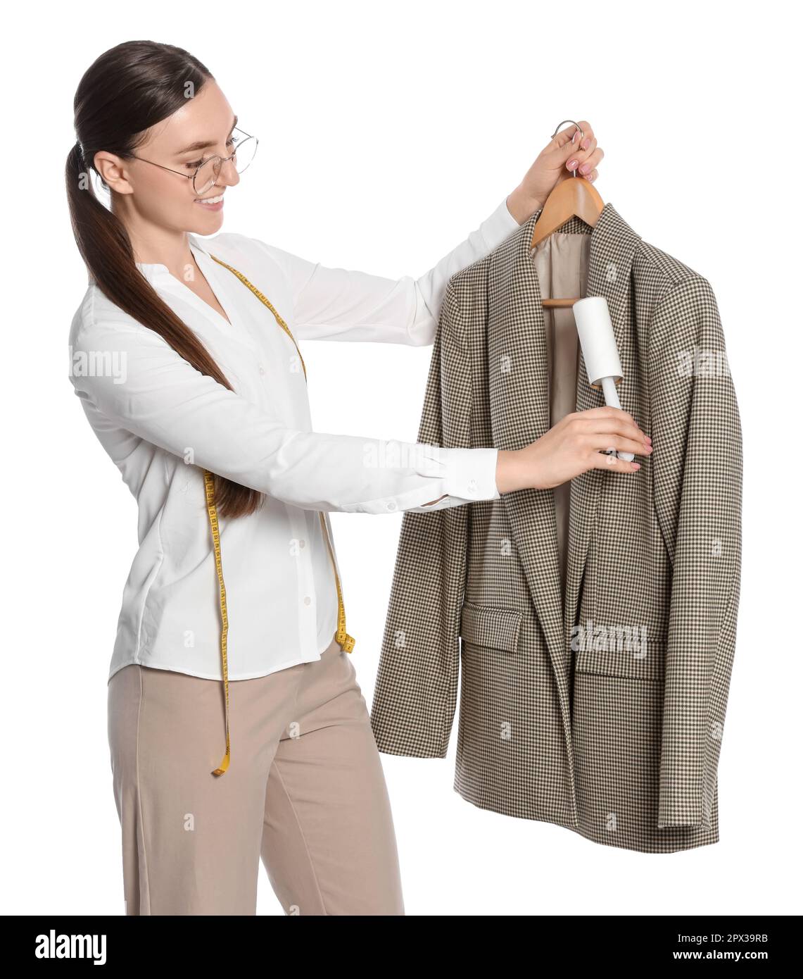 Young woman cleaning suit with lint roller on white background Stock ...