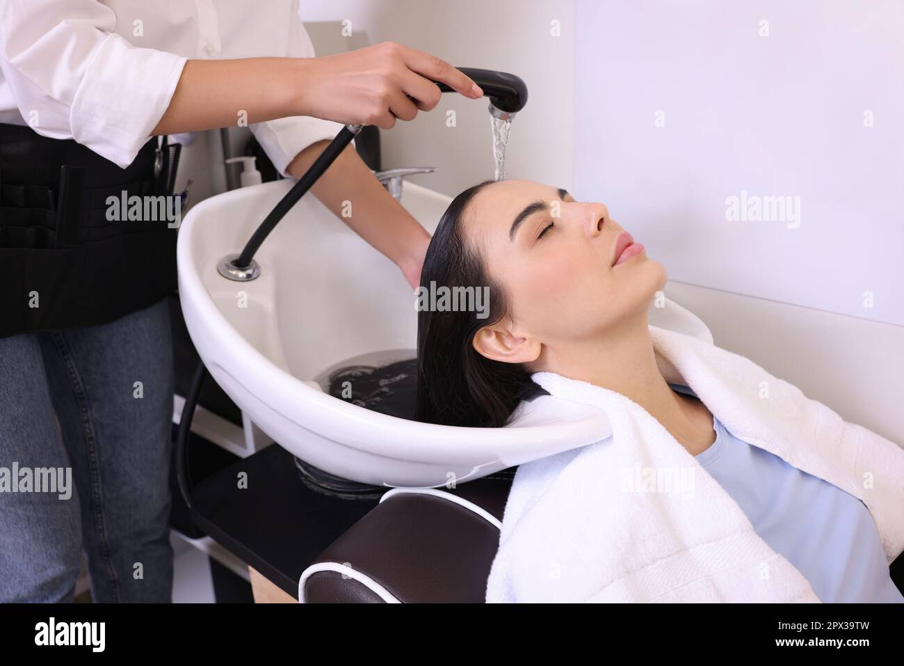 Professional hairdresser washing woman's hair in beauty salon, closeup ...