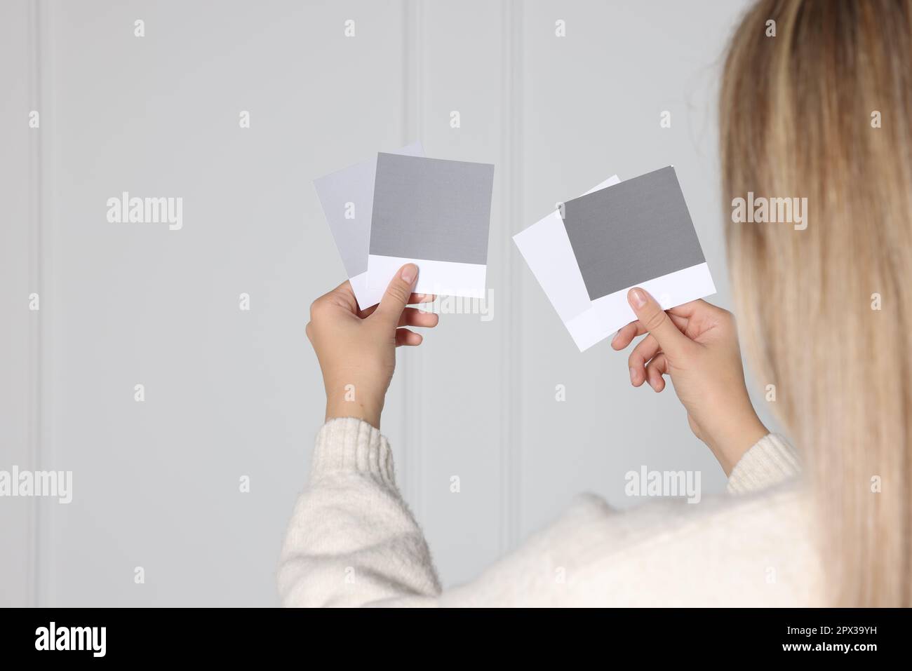 Woman choosing paint shade for wall indoors, focus on hands with color ...