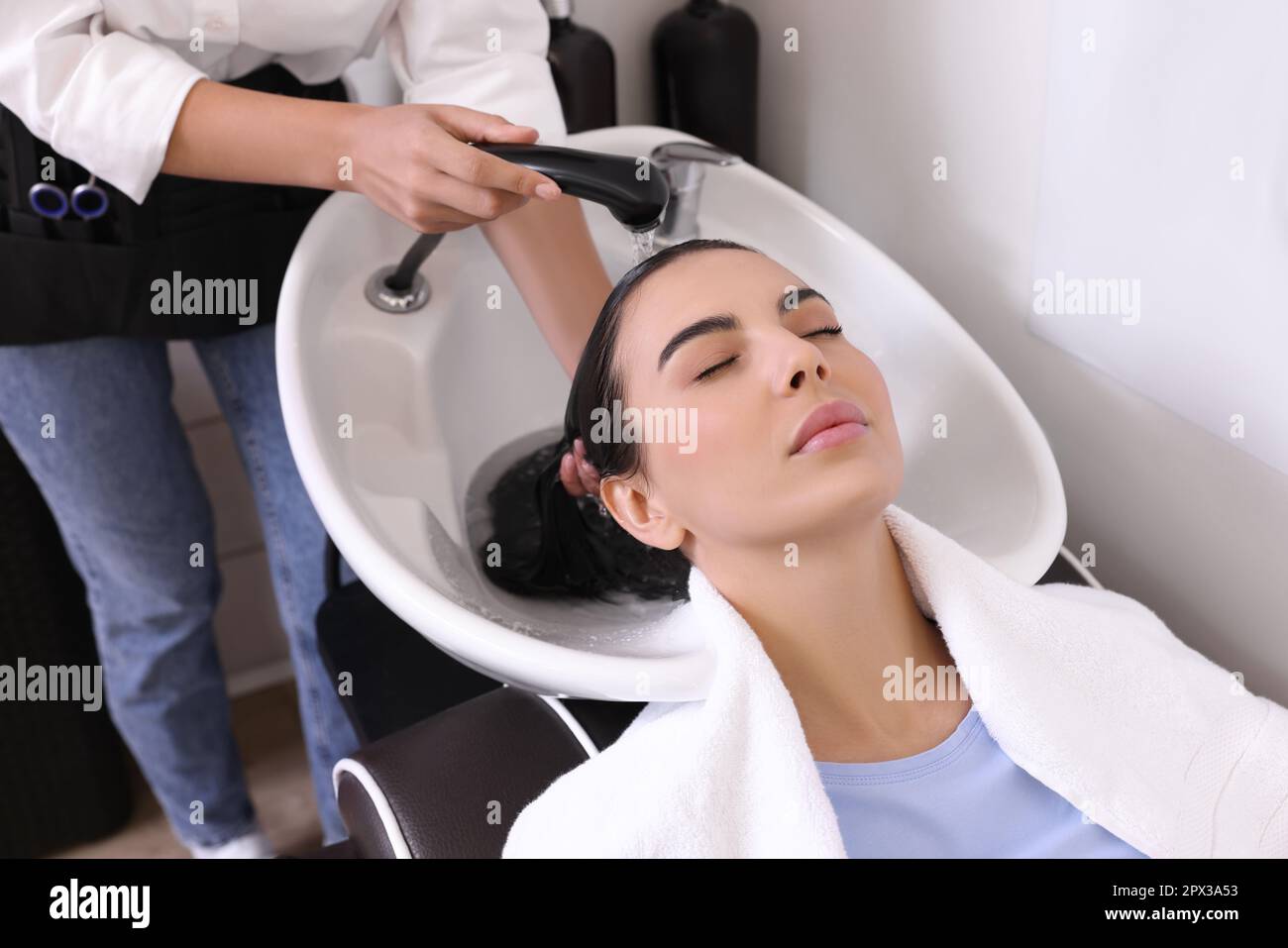 Professional hairdresser washing woman's hair in beauty salon, closeup ...