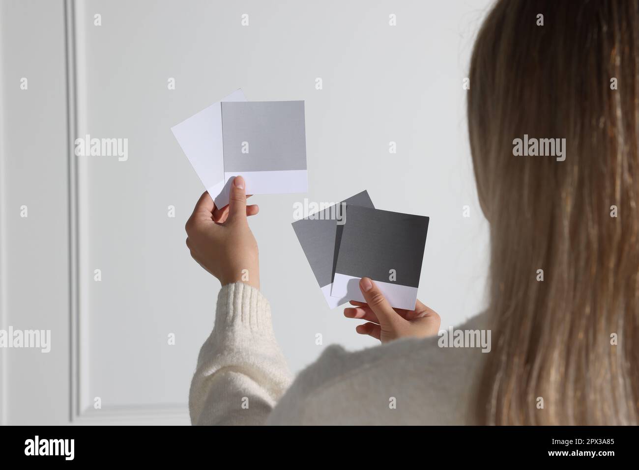 Woman choosing paint shade for wall indoors, focus on hands with color ...