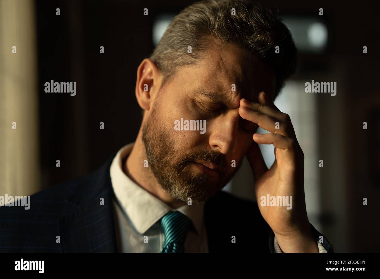 Headache, tiredness and stress. Business man in suit uses a laptop, is ...