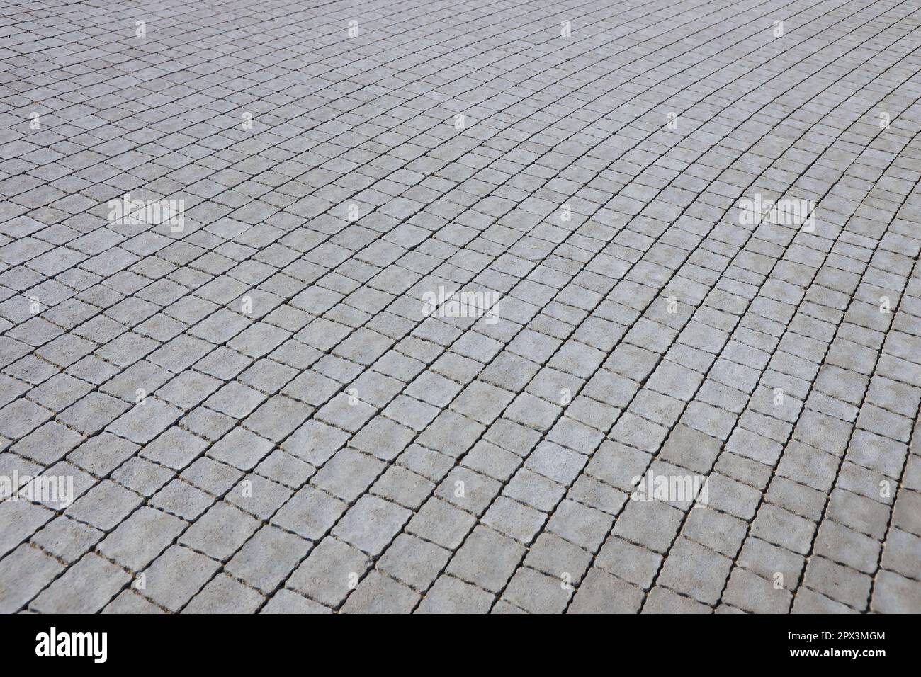 Gray color paving slabs in the pedestrian street sidewalk. Rough cobblestone pattern with many ...