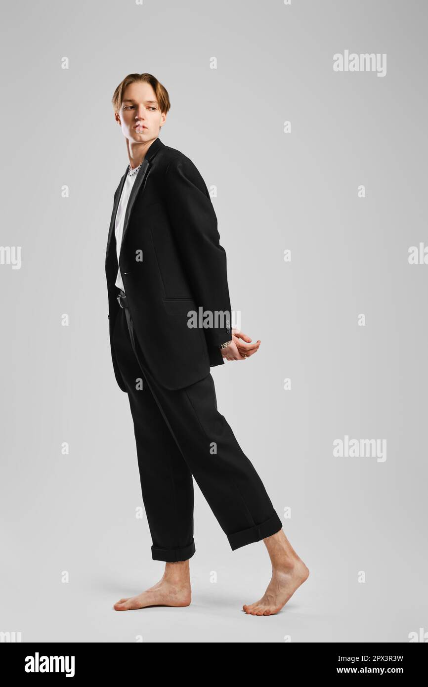 Young barefoot man in black suit posing in studio Stock Photo - Alamy