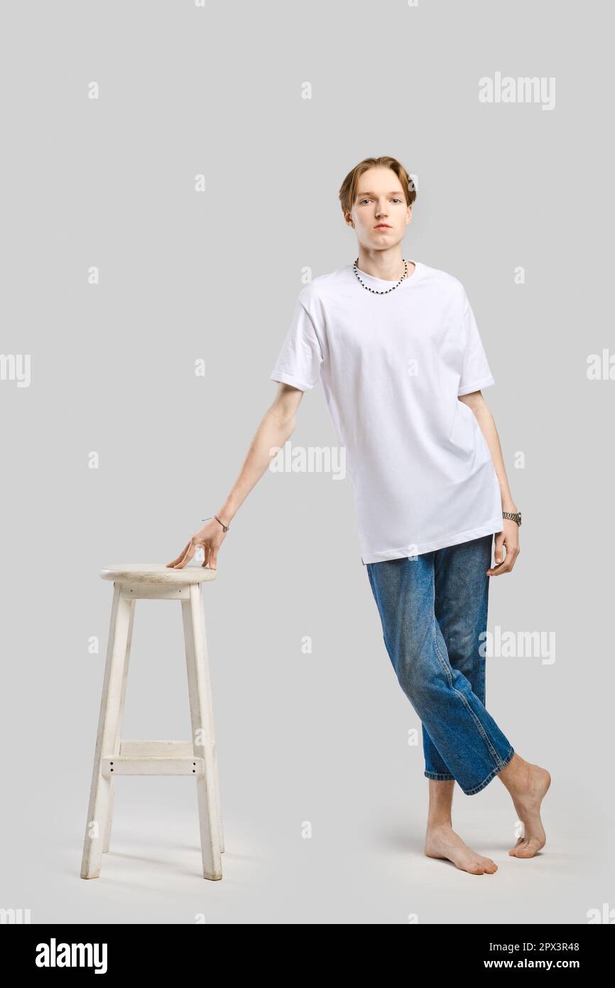 Full length portrait of young man in white t-shirt leaning to a sit of ...