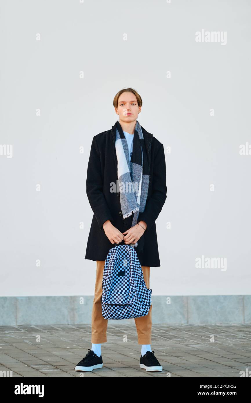Full length portrait of young student holds backpack in old wool coat ...