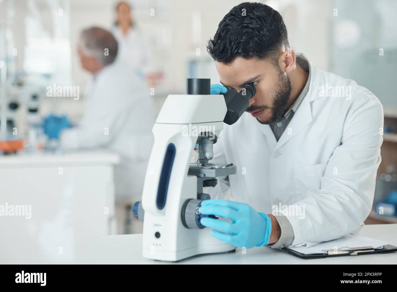 The cure takes time to perfect. a young scientist using a microscope in ...