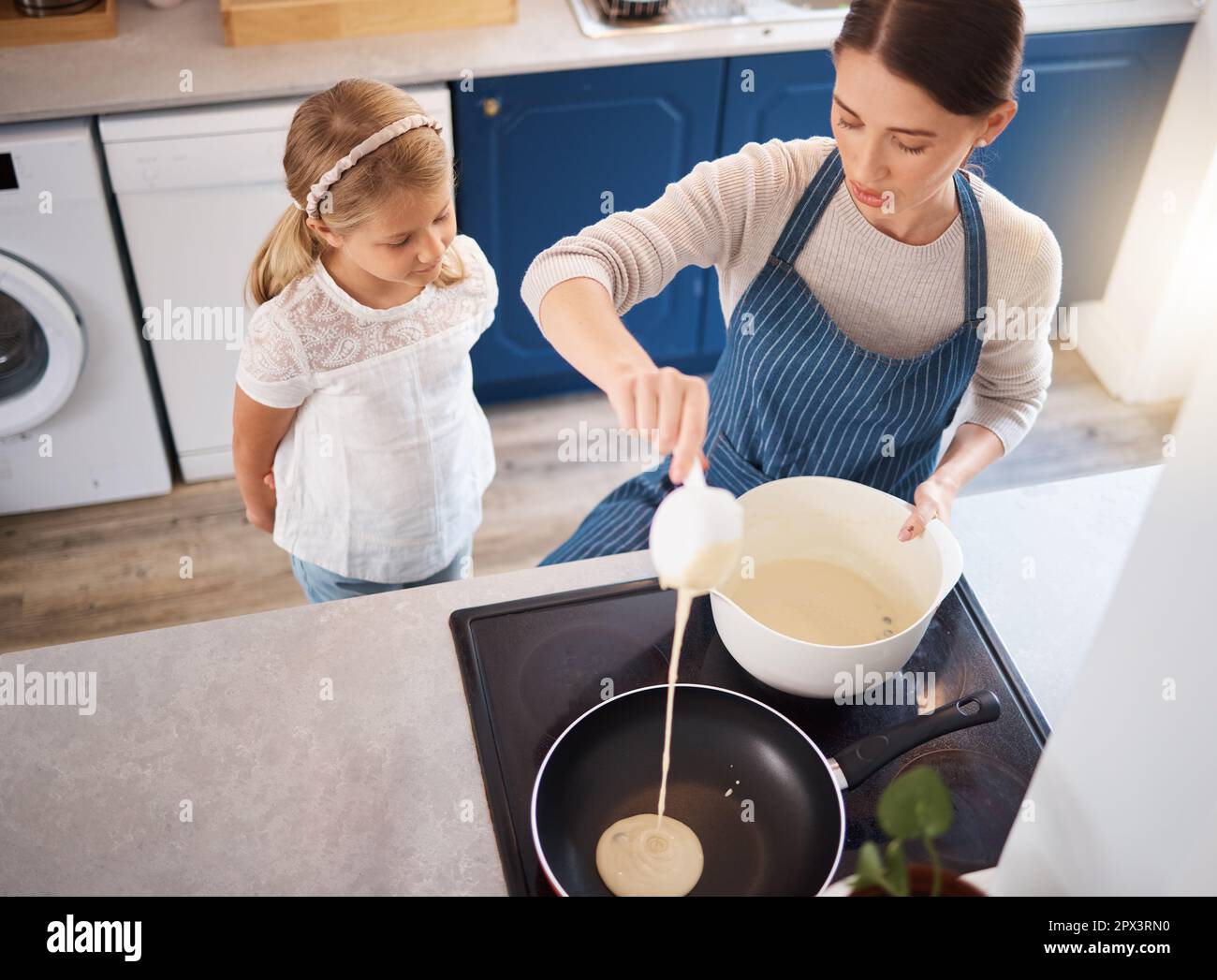 Show me how to make a good pancake, mom. a little girl watching her mother make pancakes Stock ...
