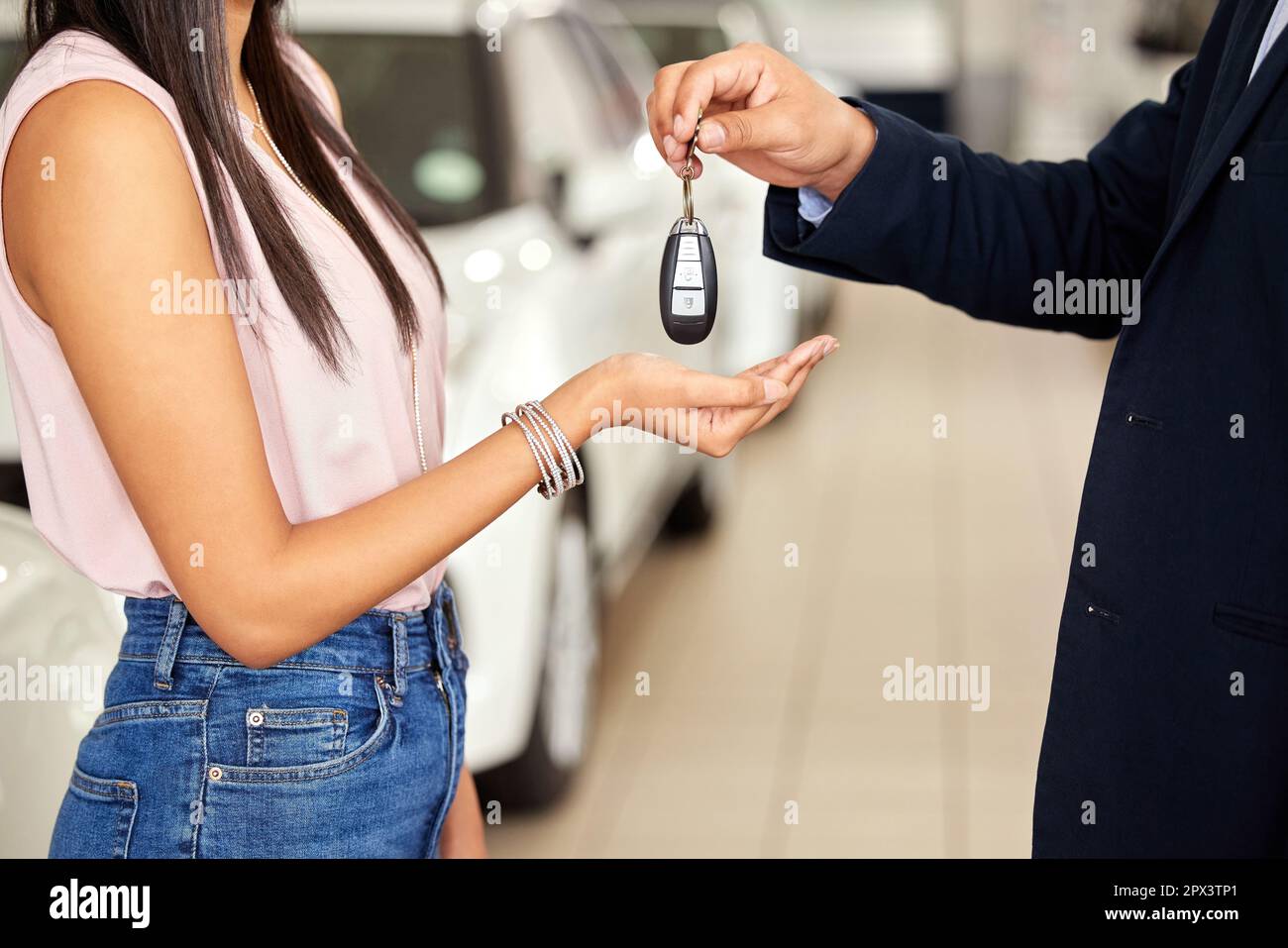 Its all yours now. a car salesman handing car keys over to a young ...