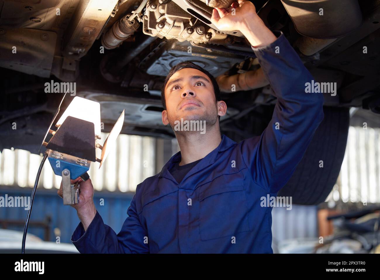 Taking a closer look. a handsome young male mechanic working on the ...