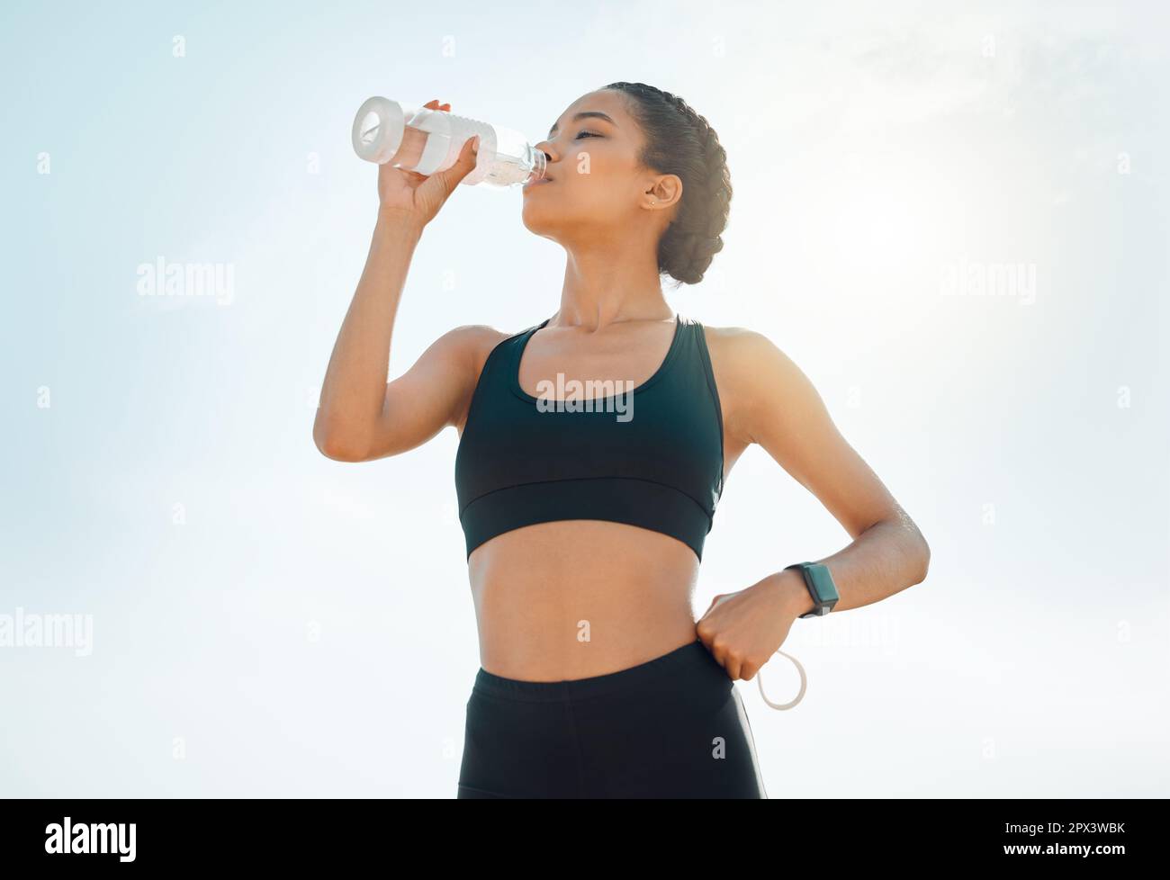 Water breaks are a necessity. a young woman re hydrating during a ...