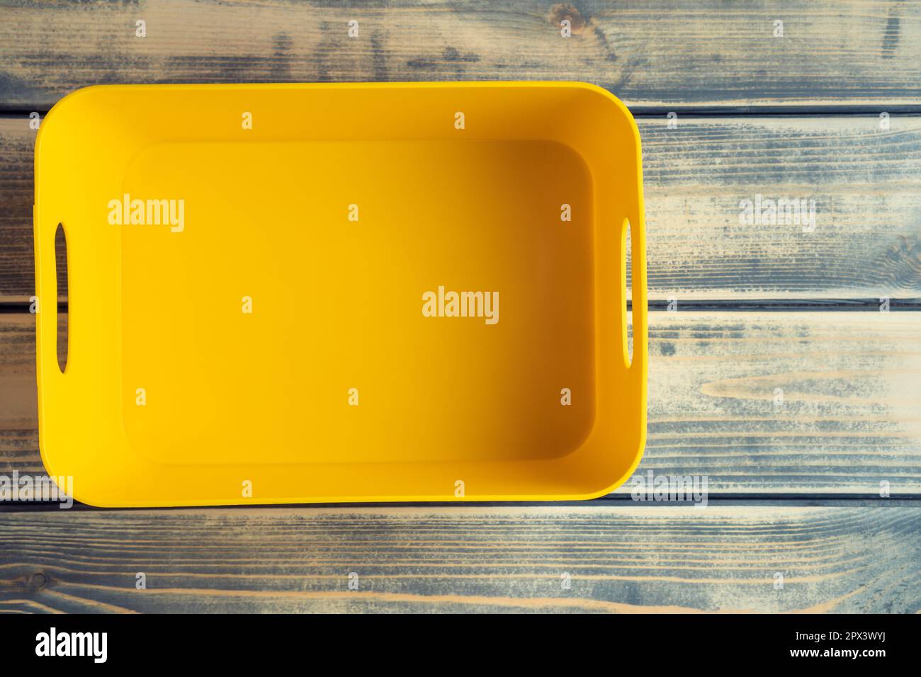 Yellow empty plastic container, box on wooden table background ...