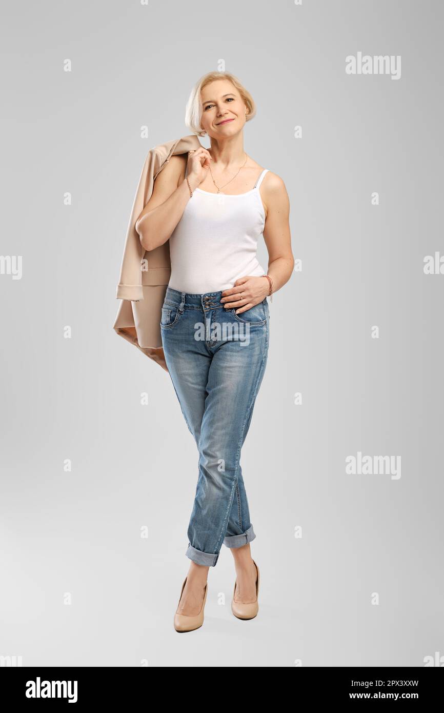 Full length portrait of senior woman in white tank top holding beige ...