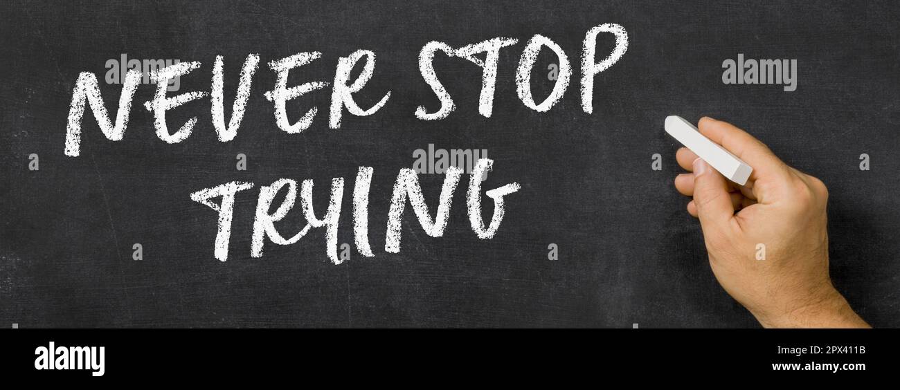 Text written on a blackboard - Never stop trying Stock Photo - Alamy