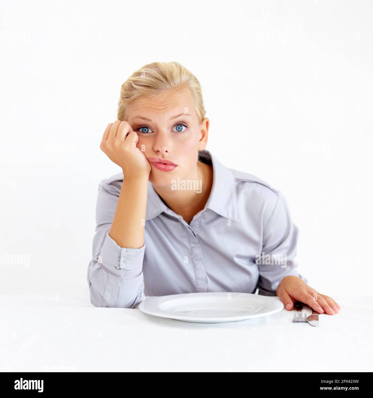 I wonder when the food will arrive...Bored young woman sitting in front ...
