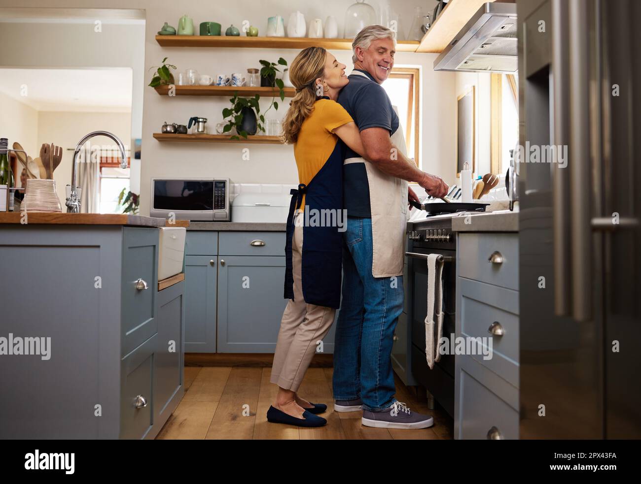 Senior couple in kitchen hug, cooking healthy food together and care in ...