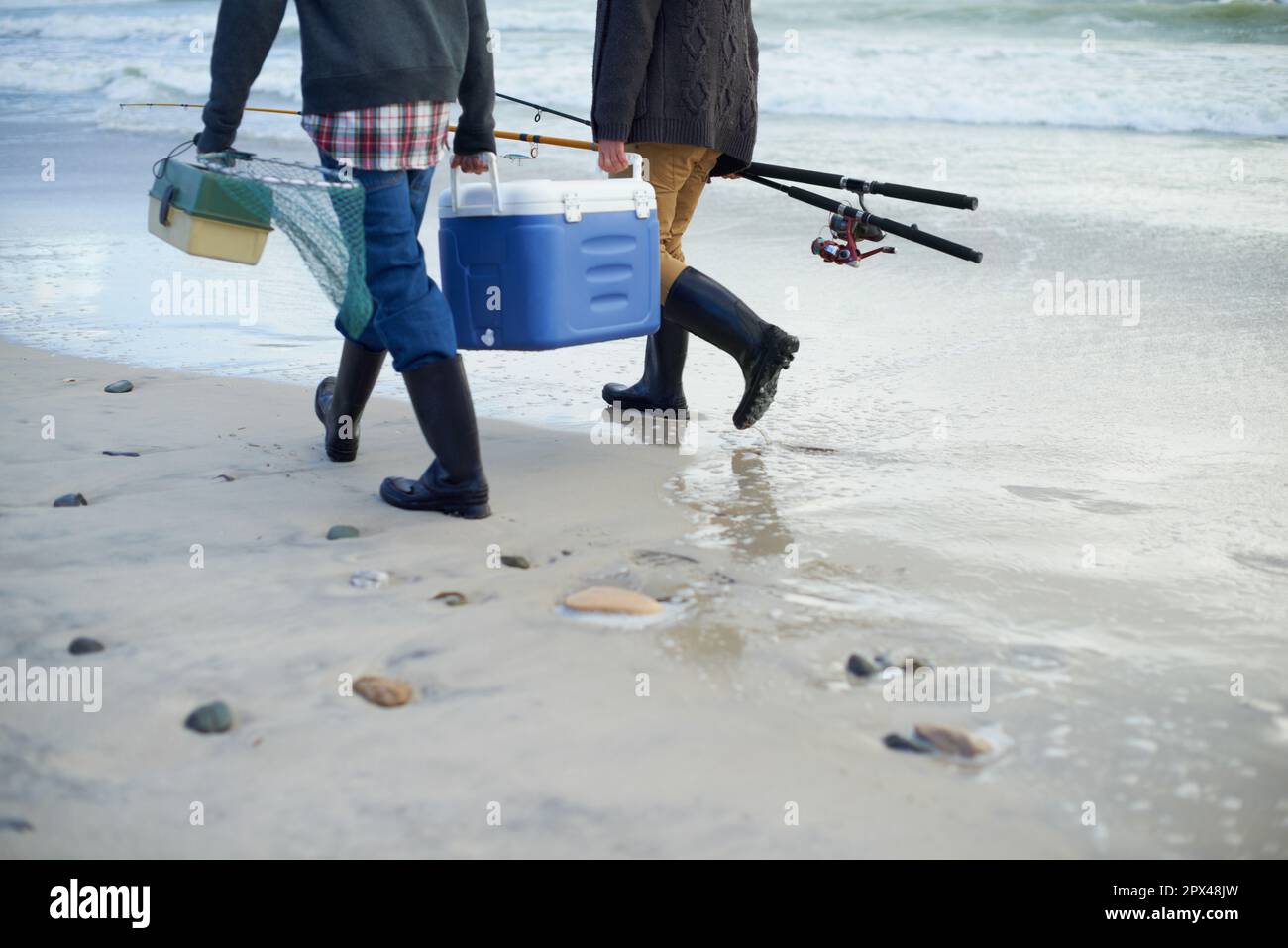 Tools of the fishing trade. Two fisherman carrying a cooler and a ...
