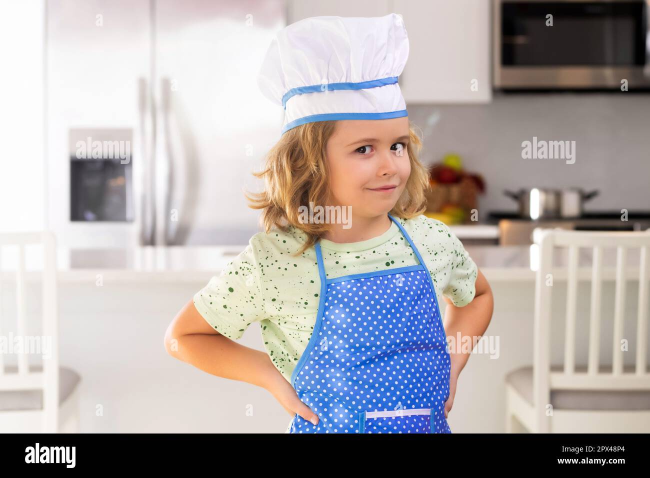Funny child stand at kitchen table have fun baking, doing bakery ...