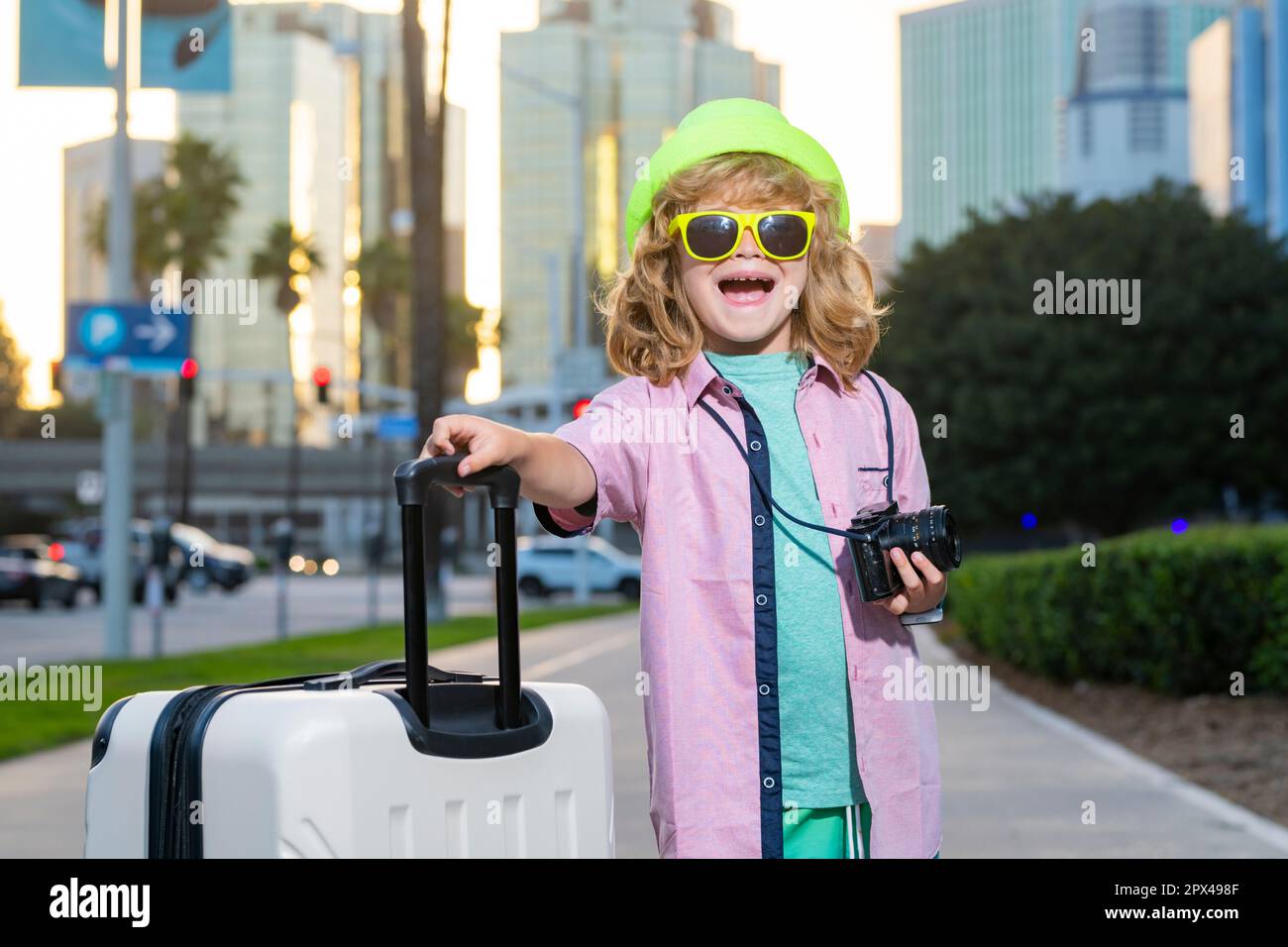 Child traveler with suitcase outdoor. Tourist kid boy having cheerful ...