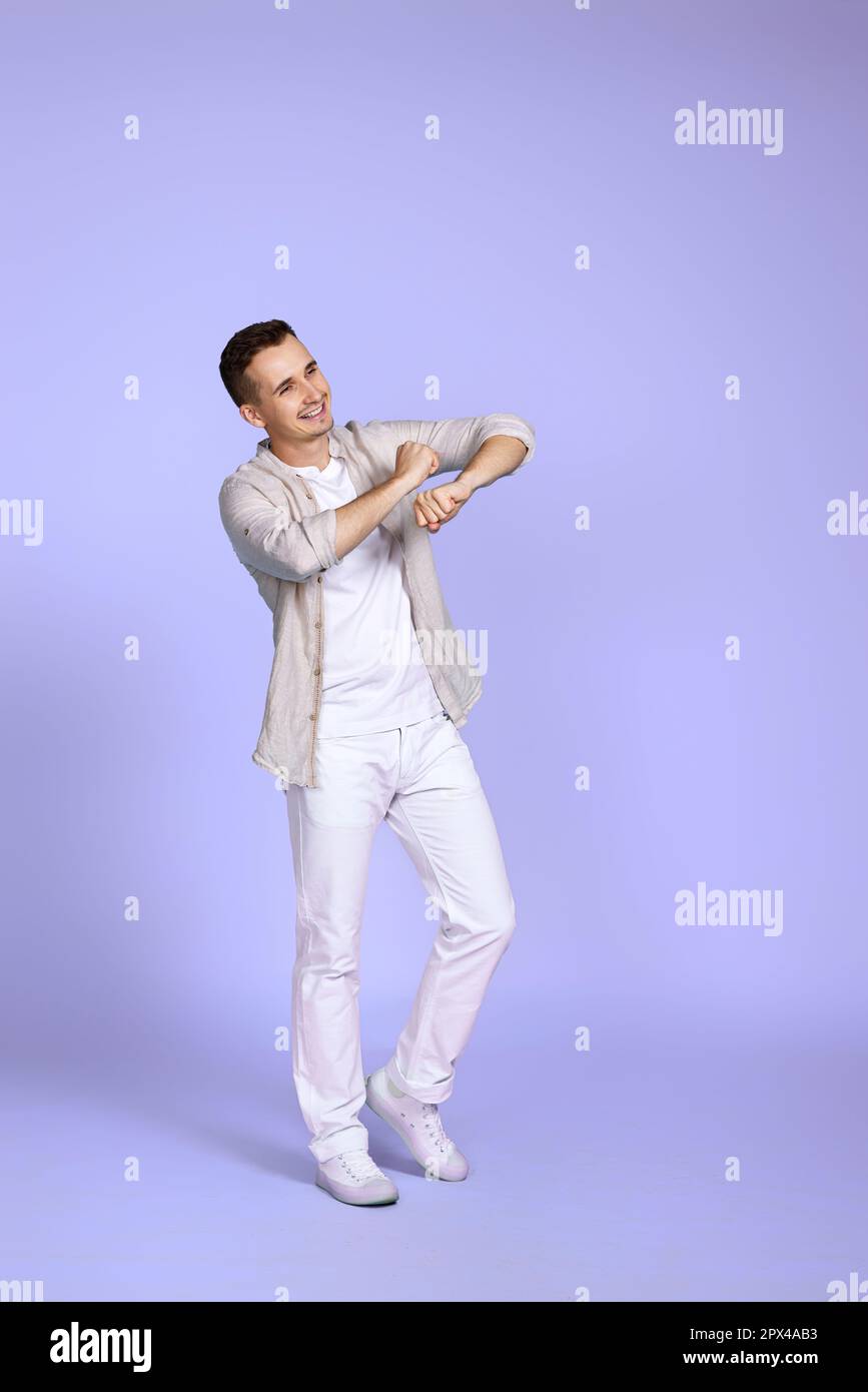 cheerful young handsome man dancing on pastel violet background ...
