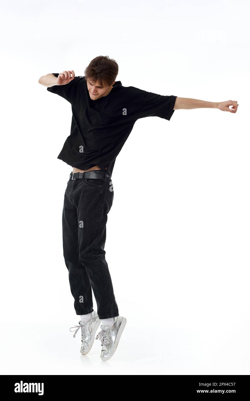 young man in black t-shirt and jeans dancing on white background. Full ...