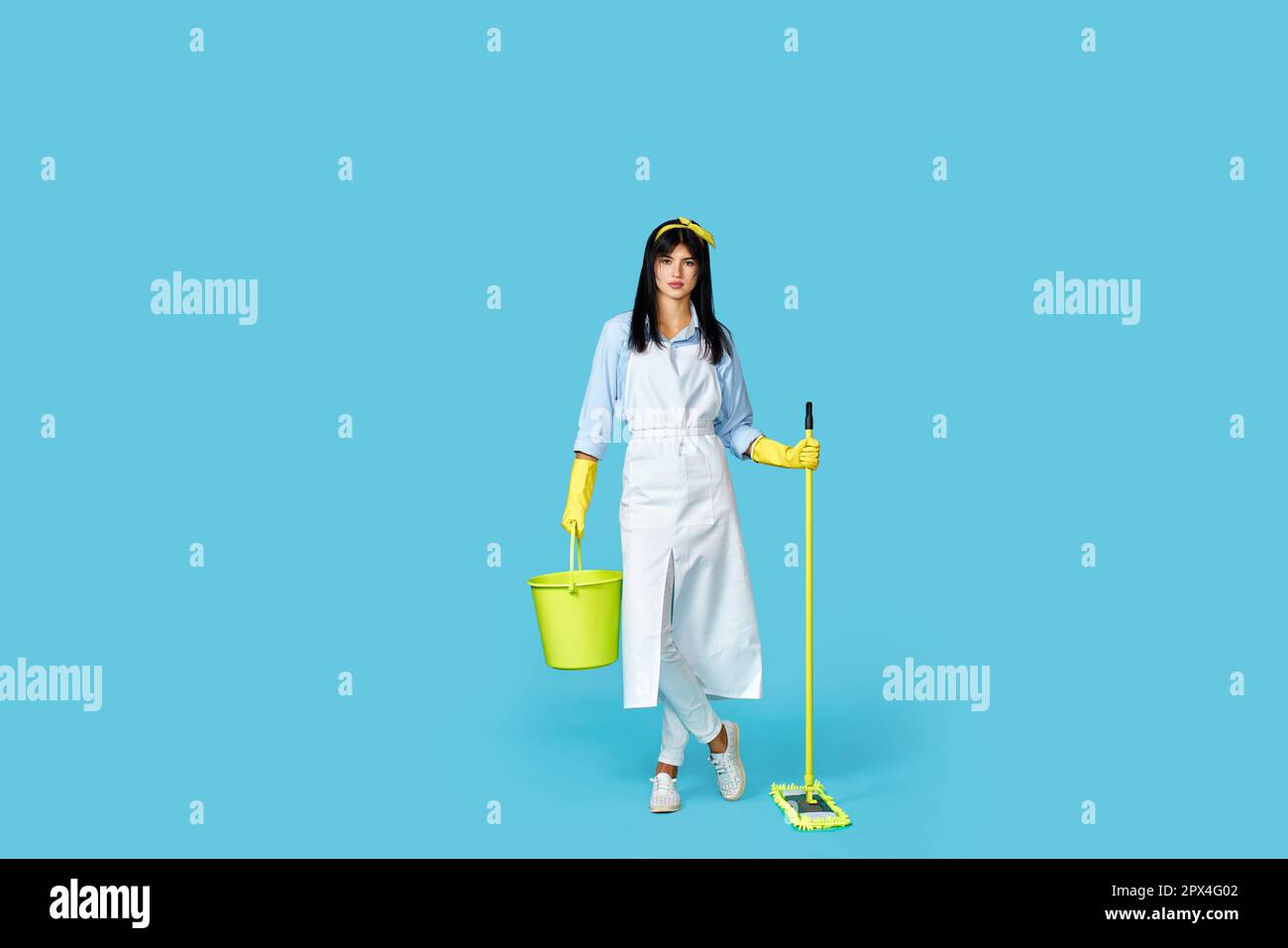 attractive woman in rubber gloves and cleaner apron washing floor with ...
