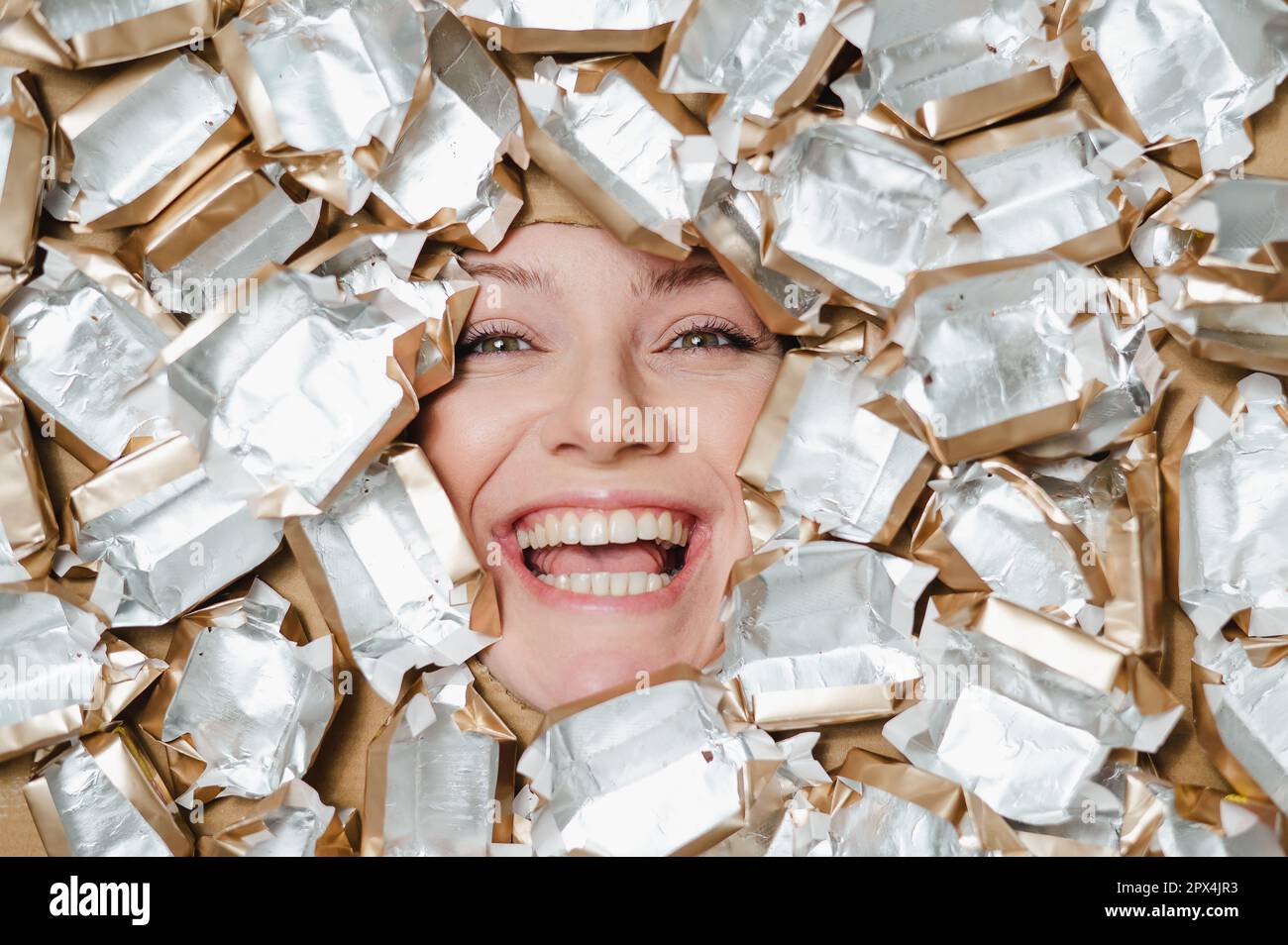 The face of a Caucasian woman surrounded by candy wrappers Stock Photo ...
