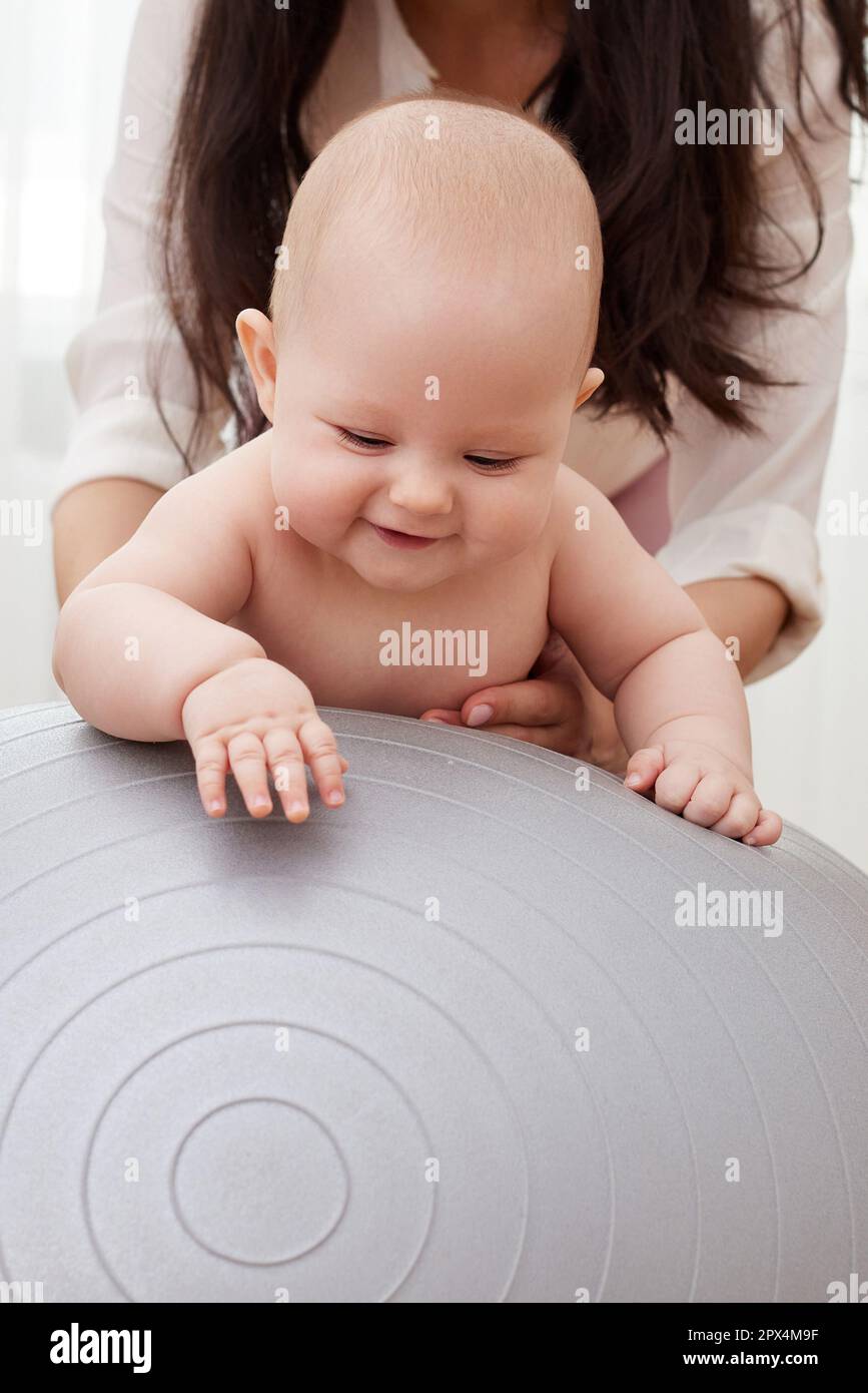 happy doing gymnastics with her baby girl on a fitness ball at home ...