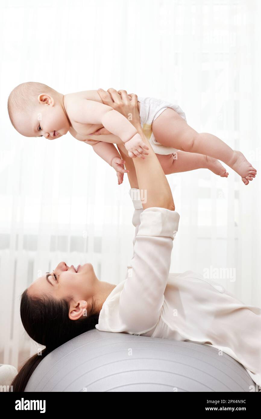 smiling mother lifting her adorable newborn baby girl in the air. Happy ...