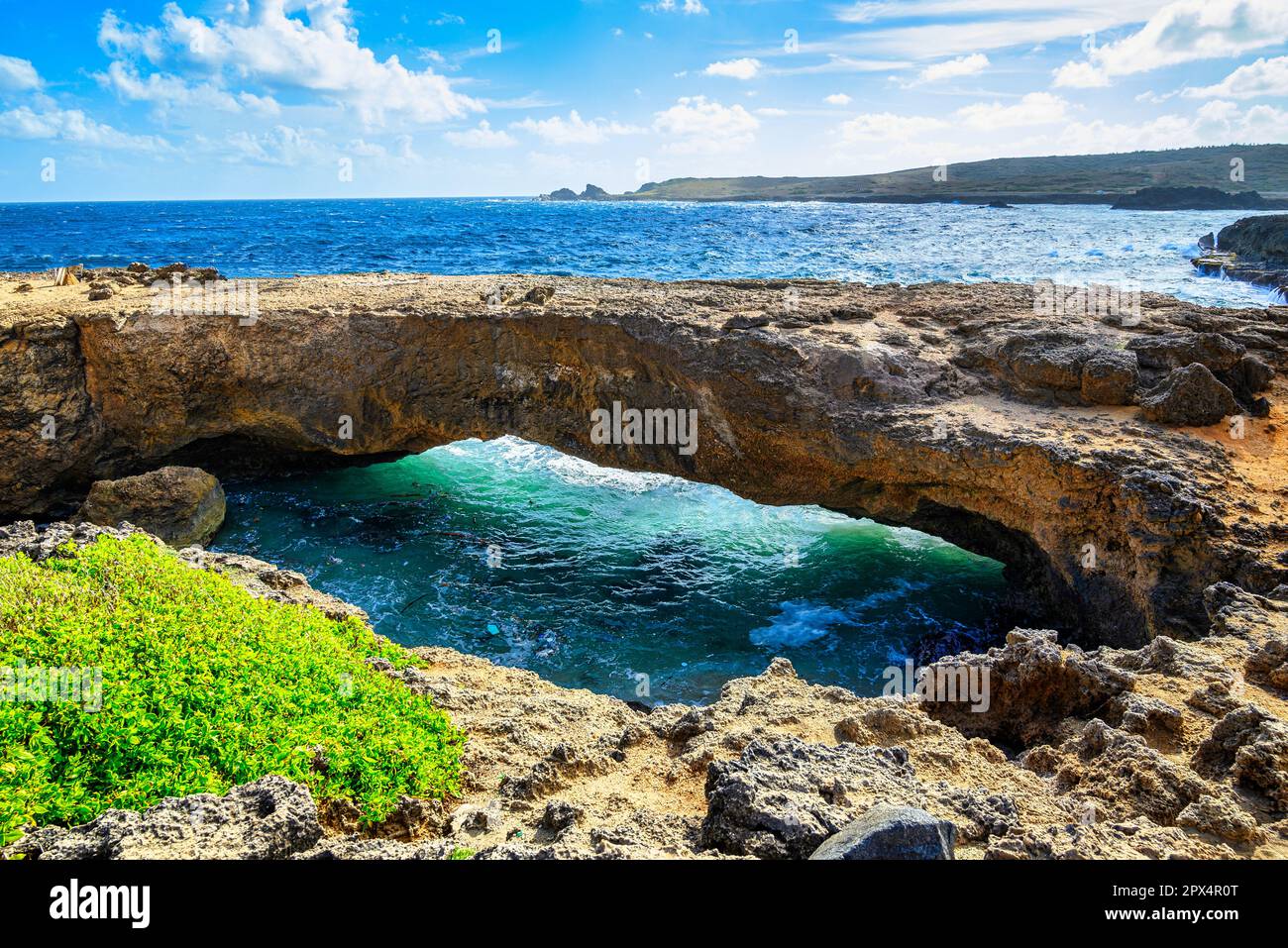 A view of the Aruba Natural Bridge in the Caribbean under blue skies ...