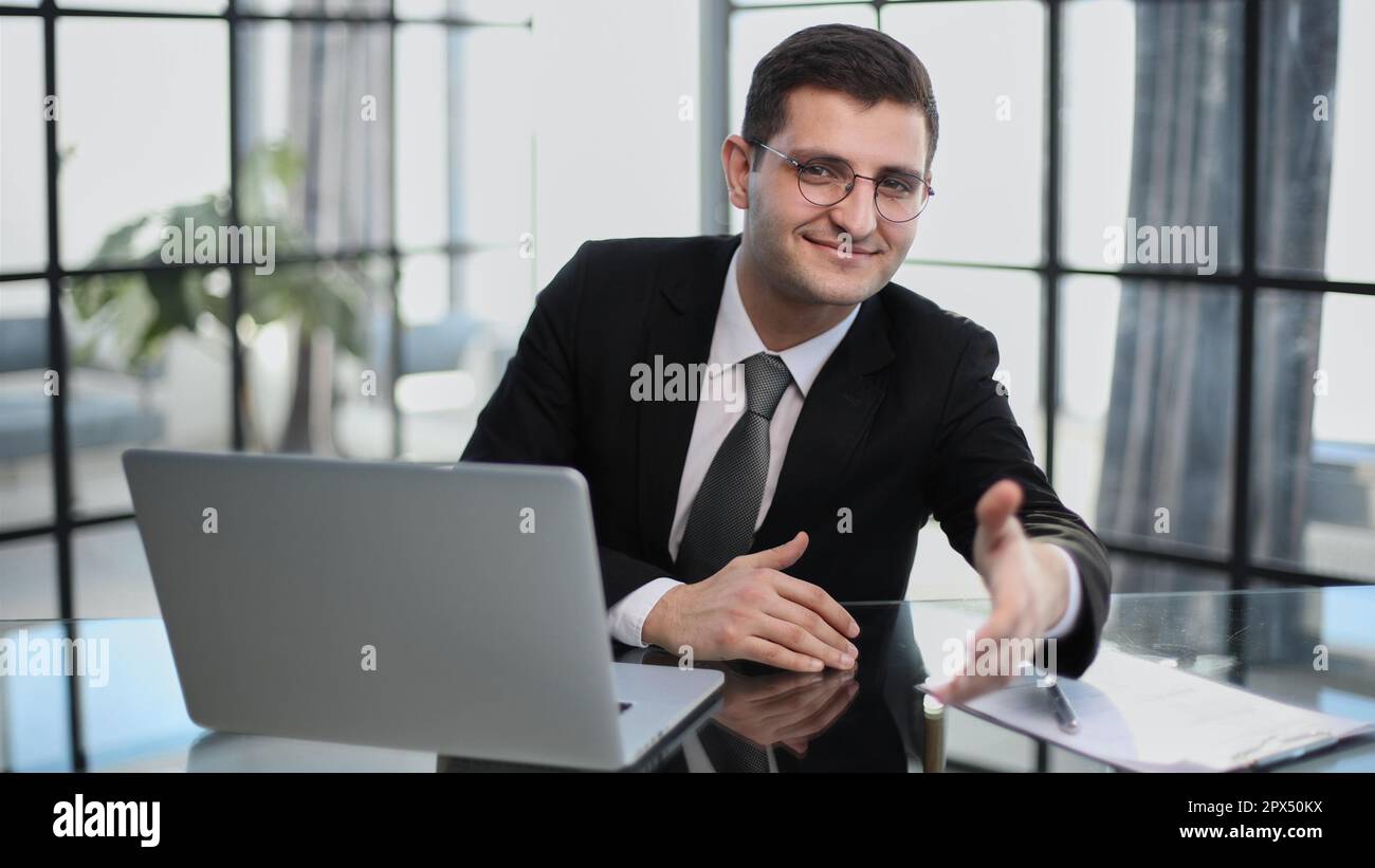 working at the computer, makes an inviting gesture, offers to sit down ...