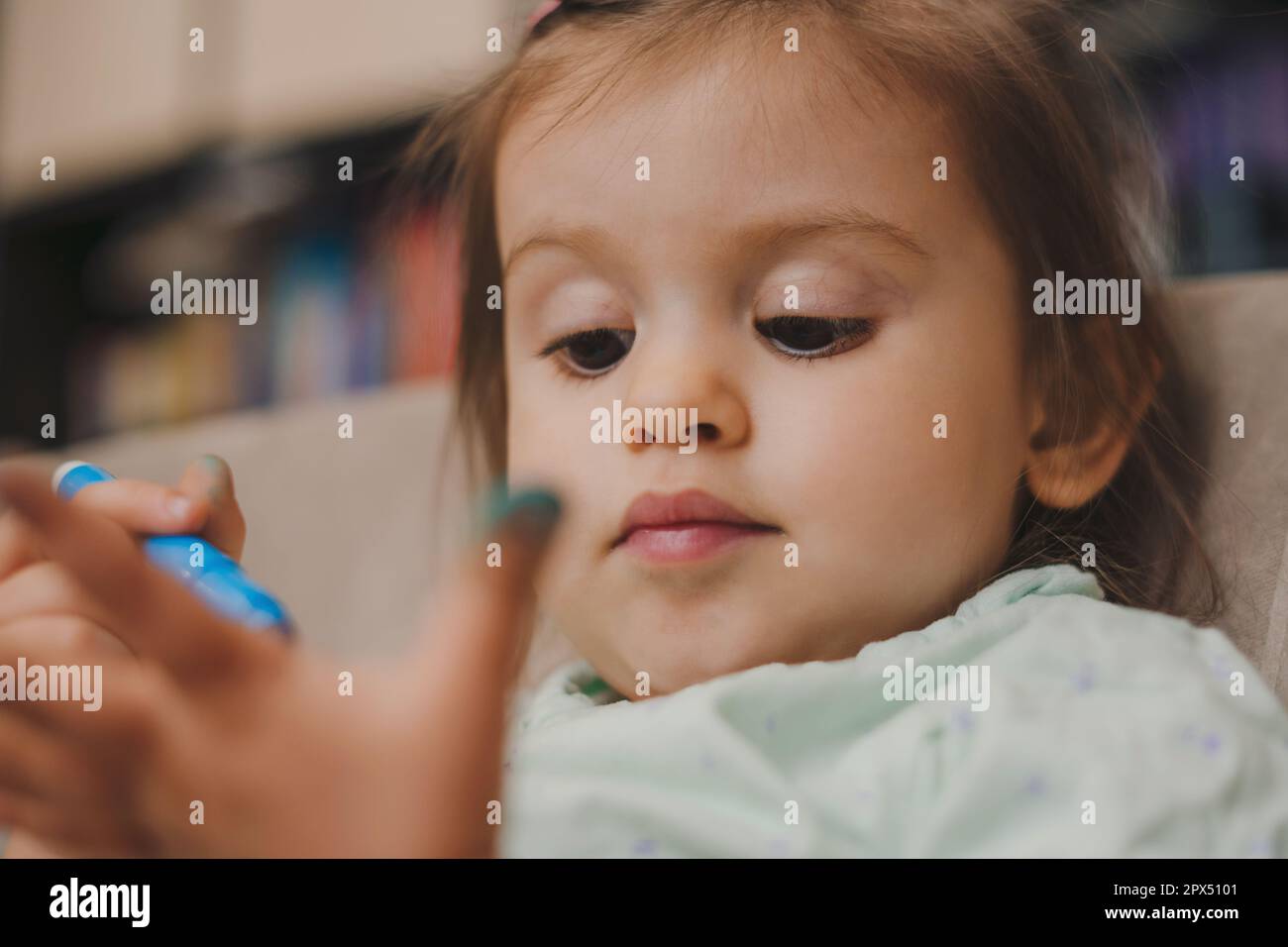 Baby girl drawing on her hand with a blue marker. The concept of ...