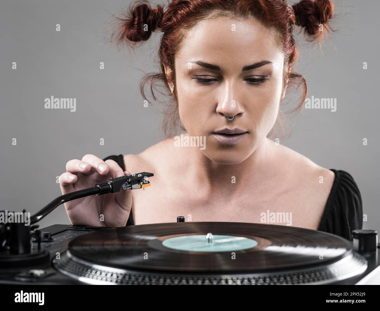 Beautiful woman about to put the needle down on the vinyl record spinning on her record player ...