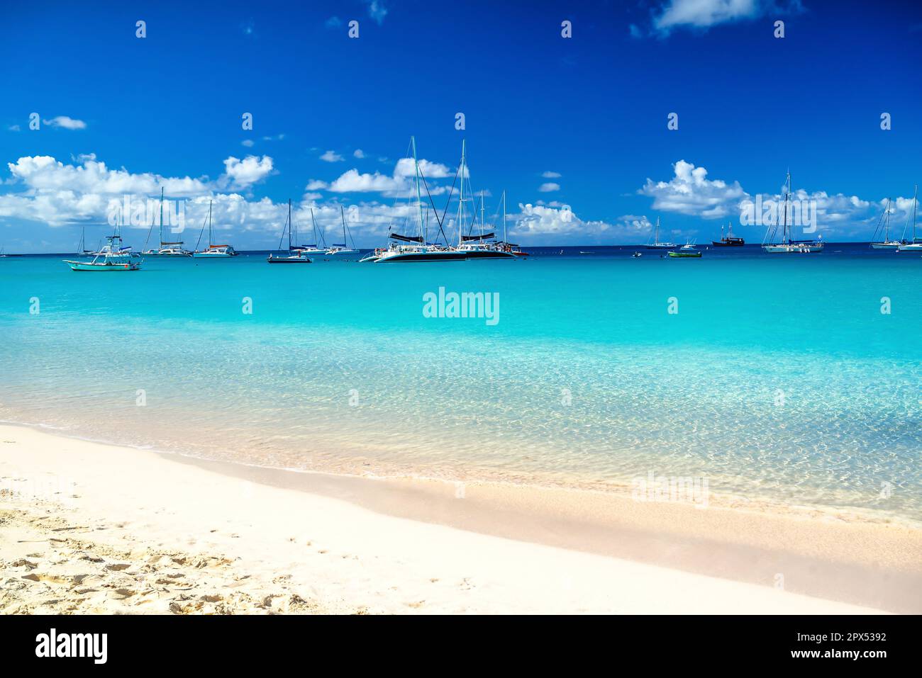 A view of the dream beach in Barbados with a blue sky and sailing boats ...