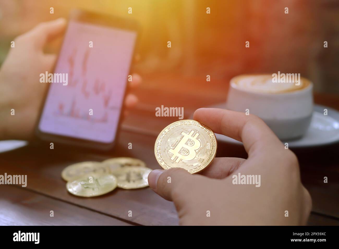 Close up of male hand holding bitcoin and mobile phone with candlestick ...