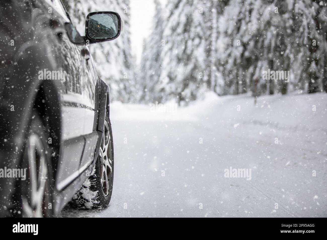 Car on a snowy winter road amid forests - using its four wheel drive ...