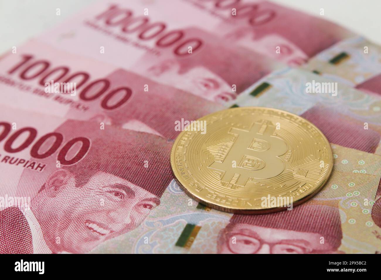 Bitcoin placing on the top of one hundred thousand rupiah bank note ...